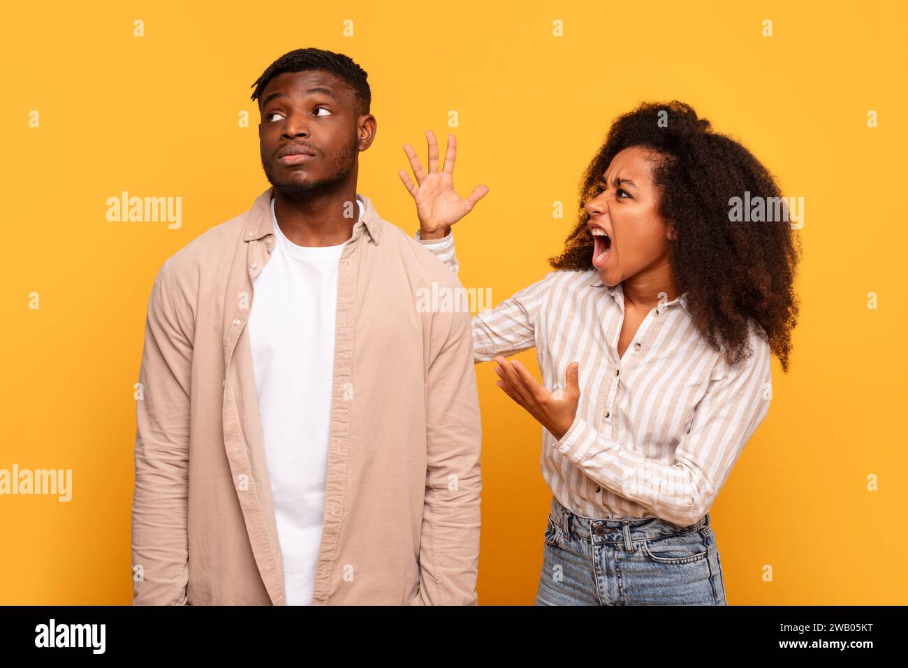 Angry black woman yelling at indifferent man on yellow background Stock ...