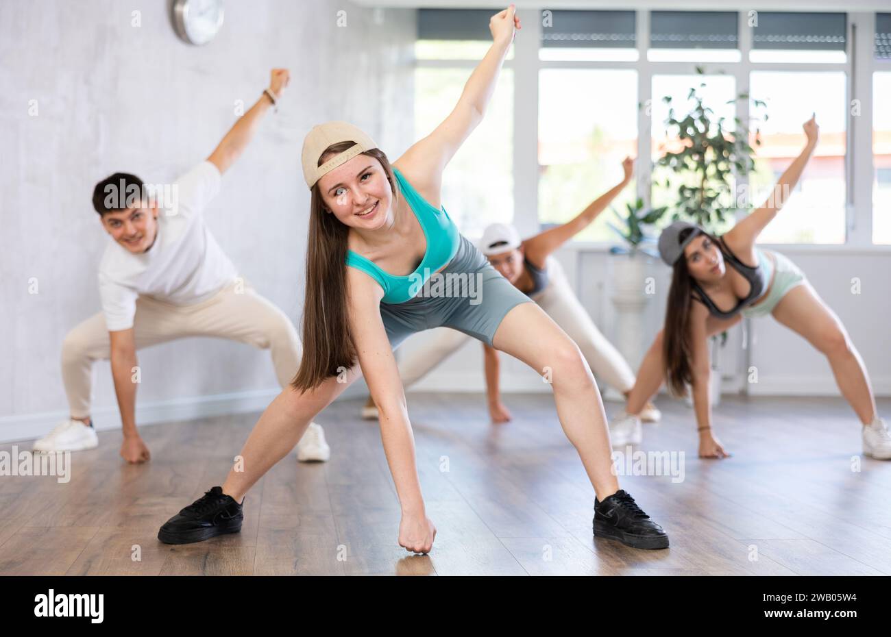 Portrait of positive teenager learning dynamic dance moves with group ...