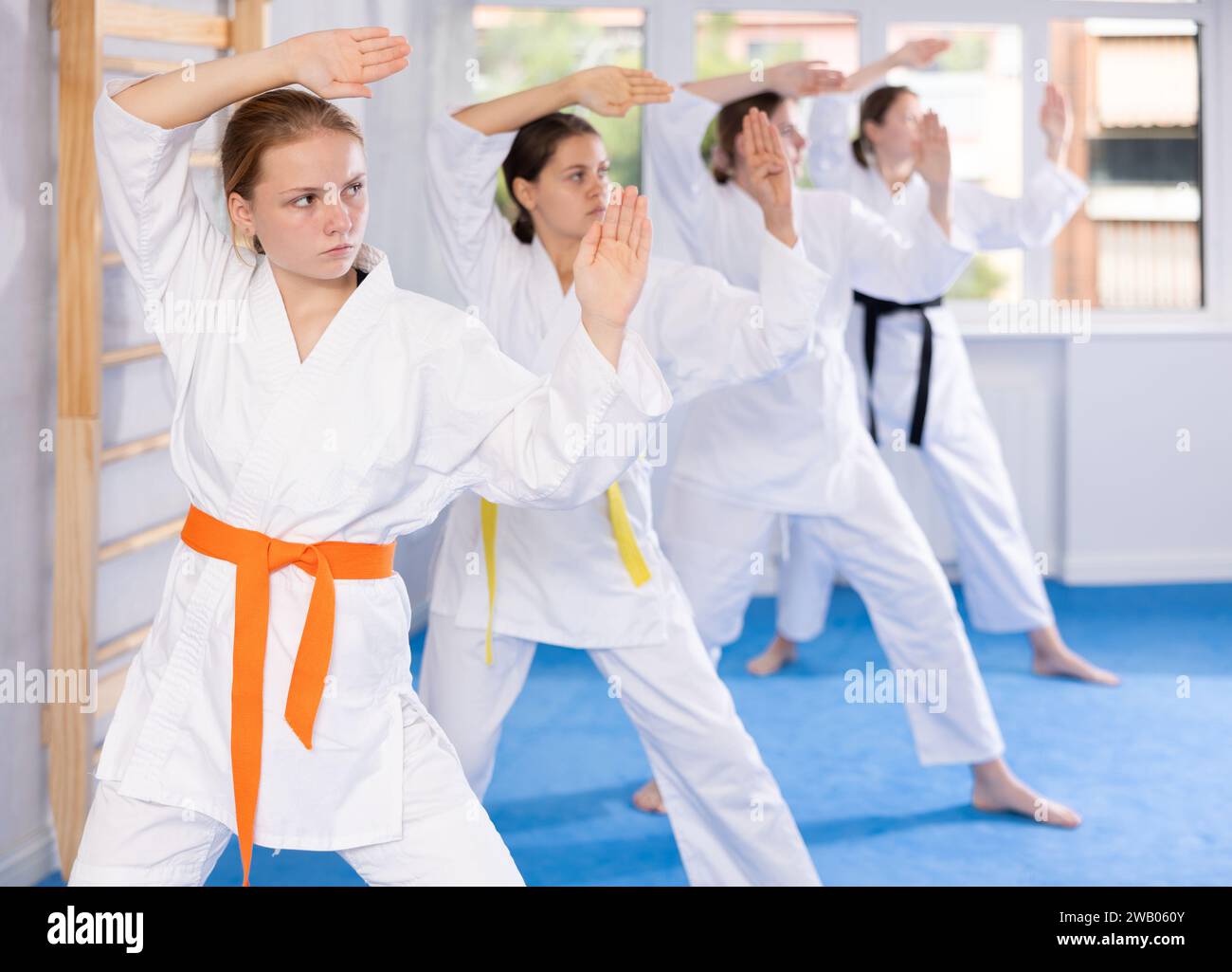Teenage girl with group in kimonos performing kata to hone martial arts ...