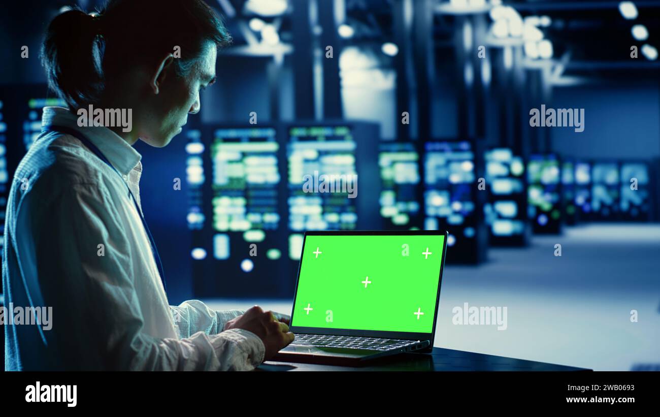 Employee using chroma key laptop to fix data center hardware clusters ...