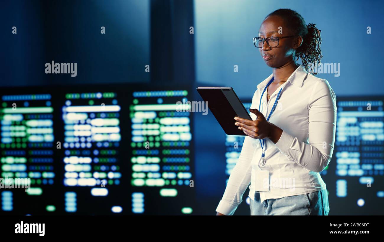 African american woman walking through data center systems providing ...