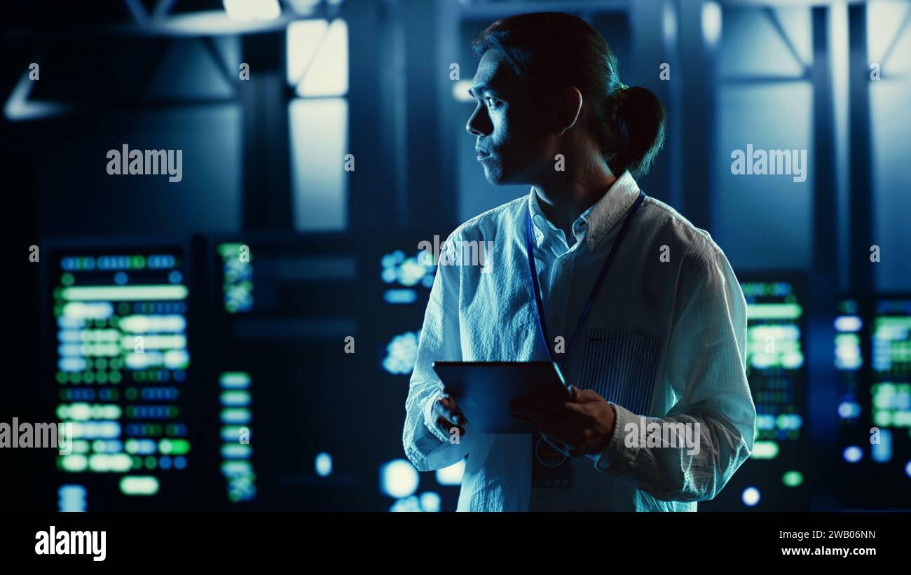 Asian employee walking through data center equipment clusters providing ...