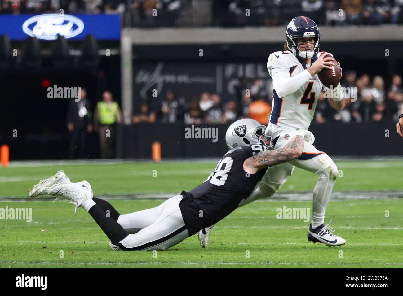 Denver Broncos quarterback Jarrett Stidham (4) is hit by Las Vegas Raiders defensive end Maxx ...