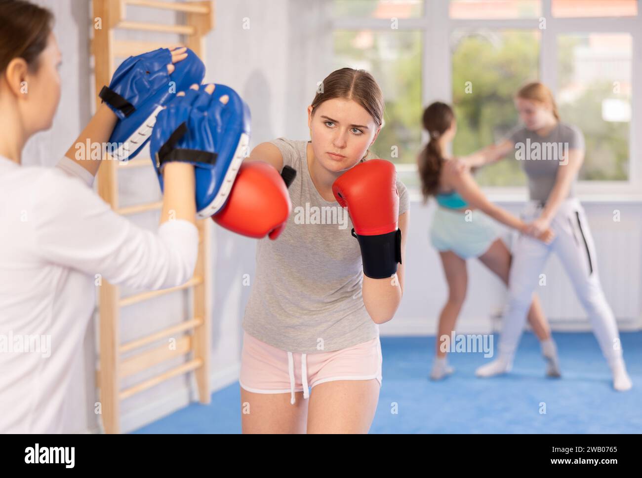Girls works out strength and speed of boxing punch mitts with help of ...