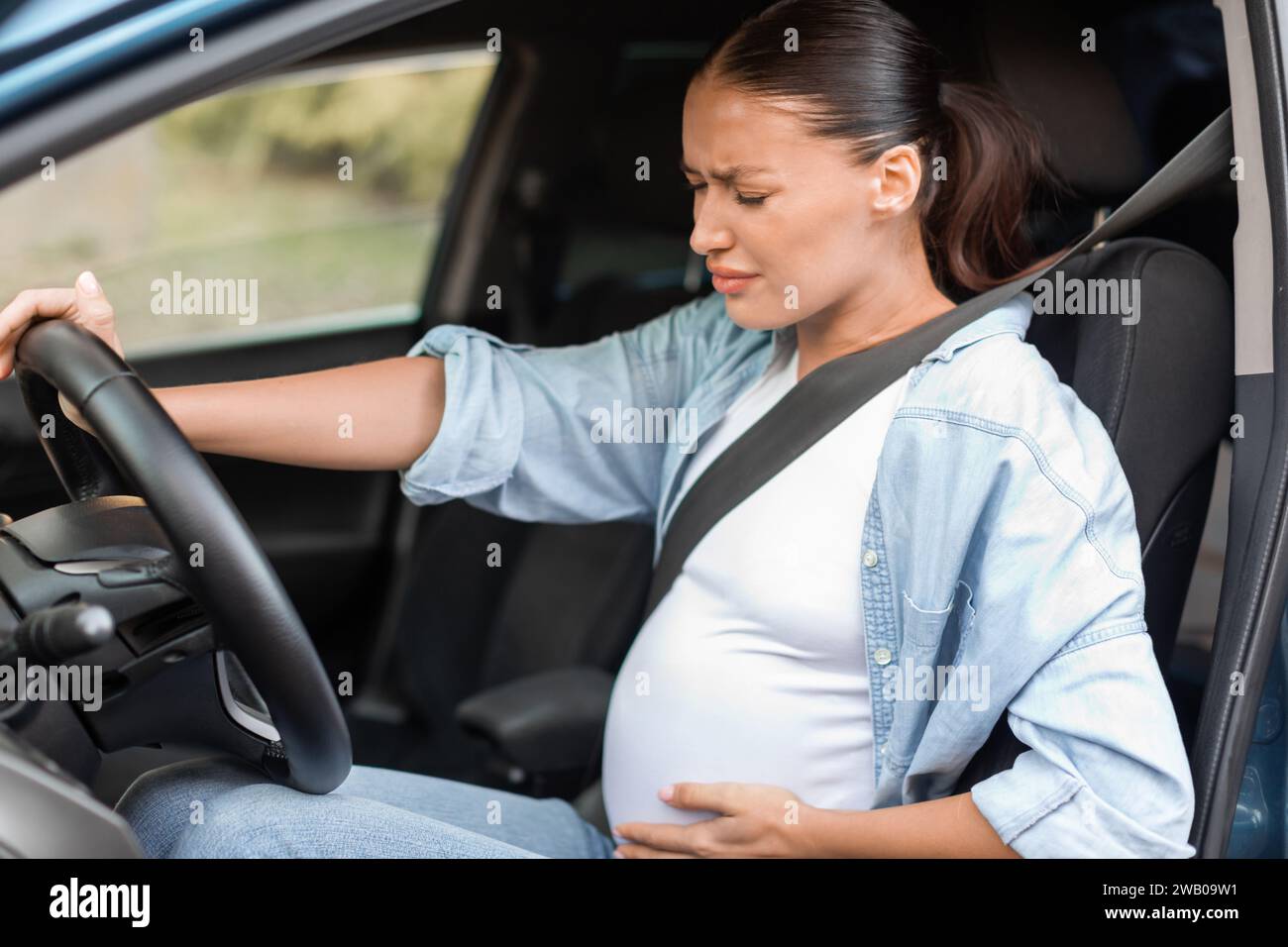 Pregnant woman driving car touching belly having sudden contractions ...