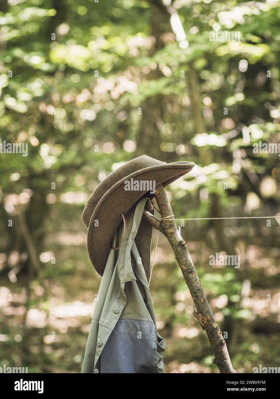 Outdoor hiking clothes green olive hat and shirt hanging on a stick in ...