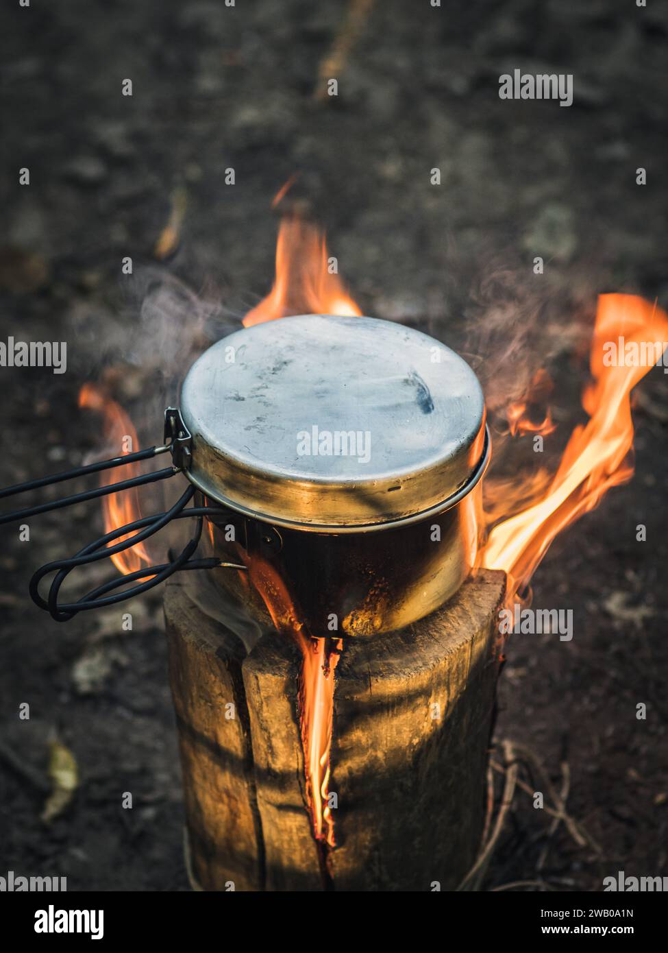 Water boiling in a metal pot on Swedish Fire Log. Burning a Swedish ...