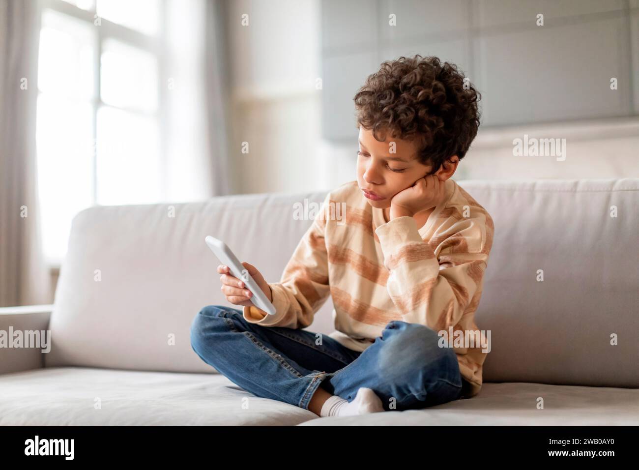 Upset Black Boy Using Mobile Phone While Relaxing On Couch At Home ...