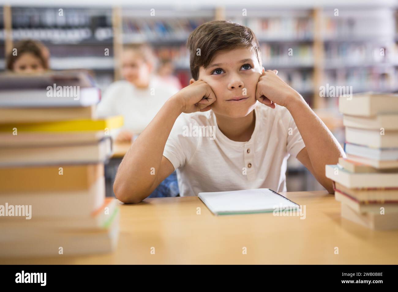 Bored teenage boy trying to prepare for exam in library Stock Photo - Alamy