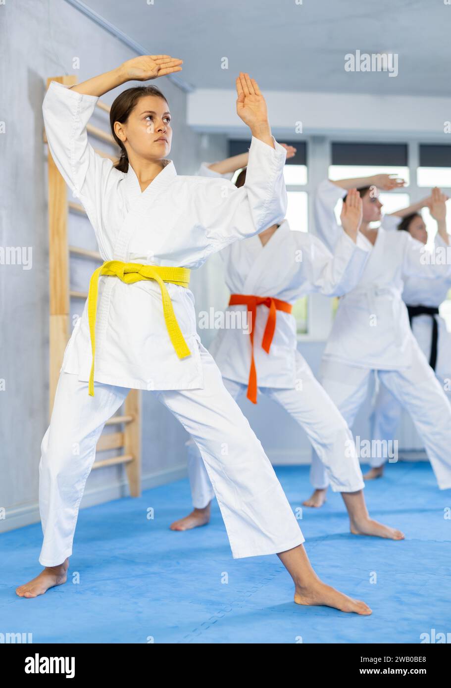 Teenage girl with group in kimonos performing kata to hone martial arts ...