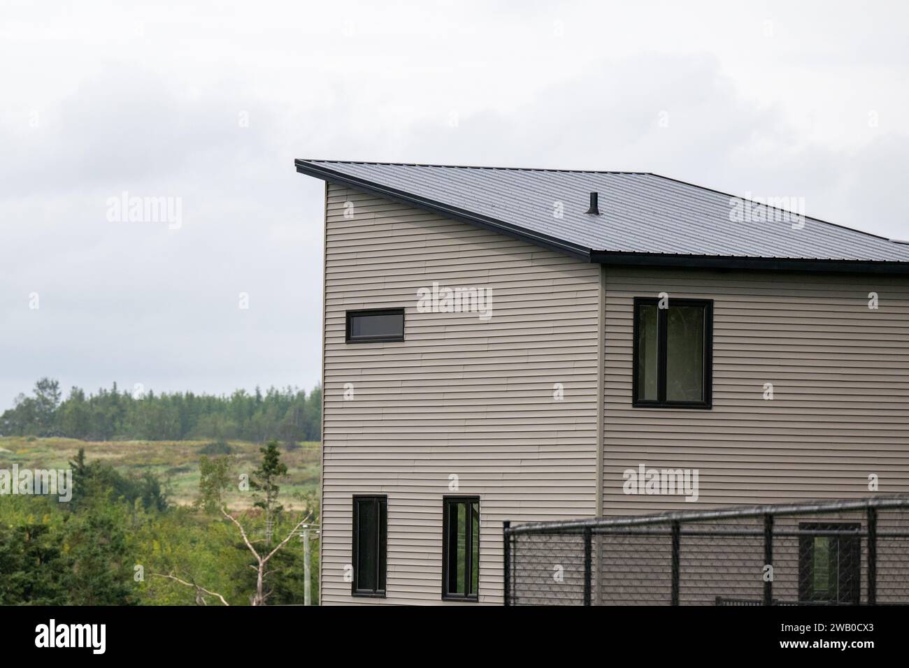 The exterior corner of a modern wooden tiny house. It has grey vinyl ...