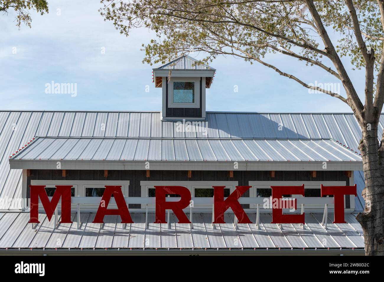 A vibrant red illuminated market sign on the roof of a rustic building ...