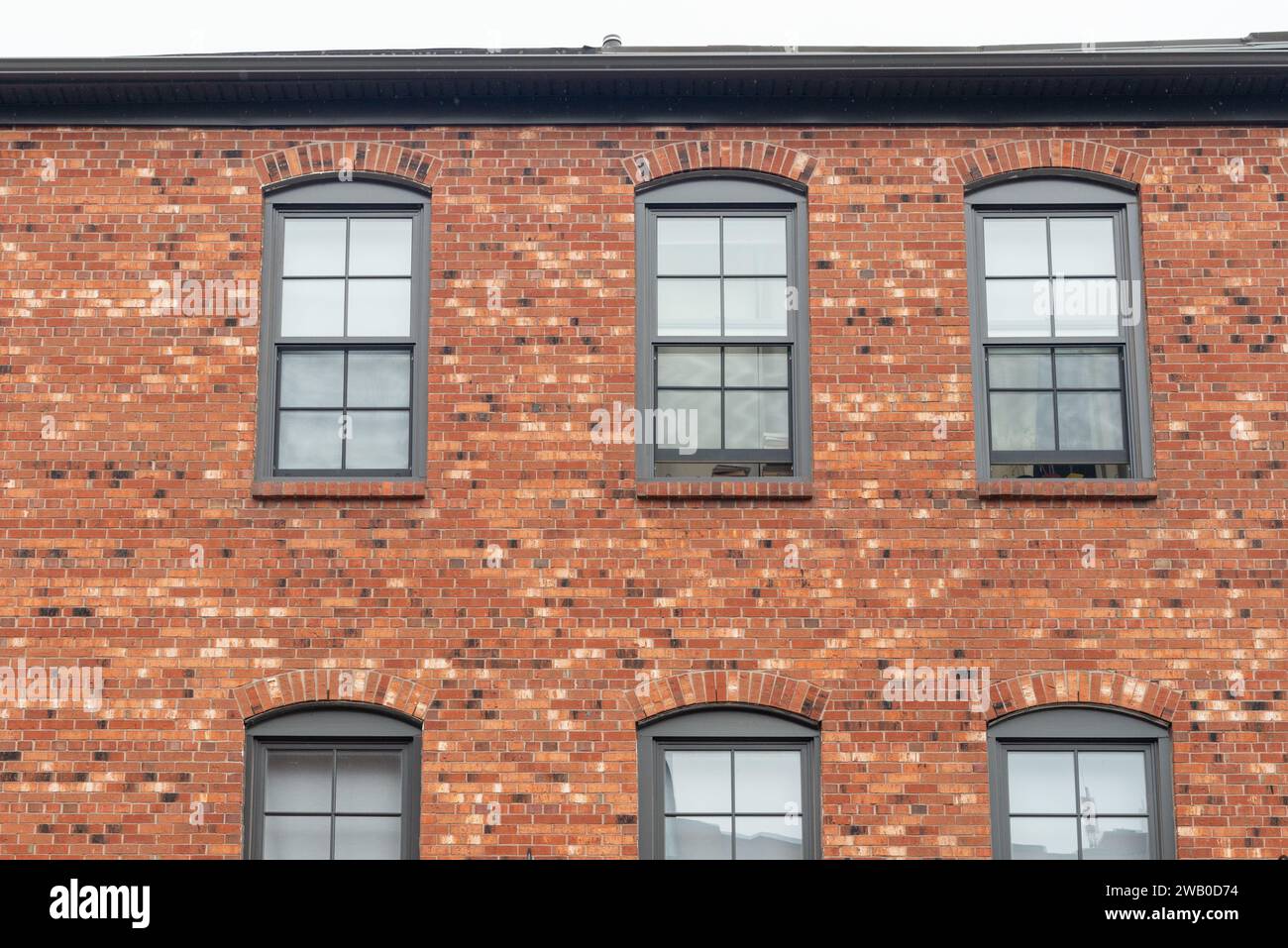 The exterior of an old red brick building with six glass double hung ...