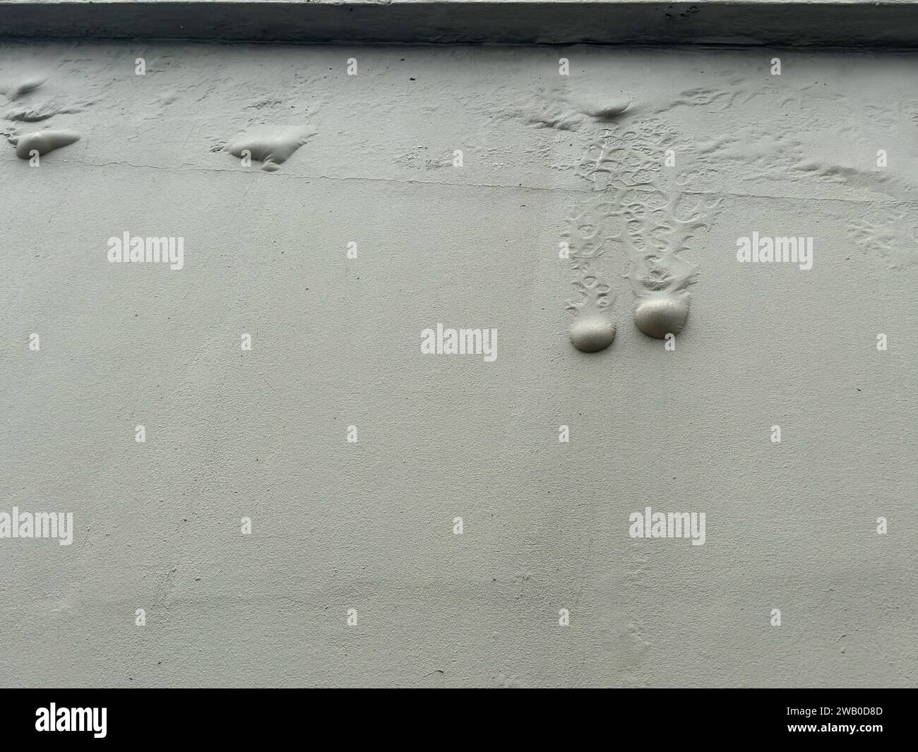 An exterior grey cement wall painted with a texture. Bubbles or ...