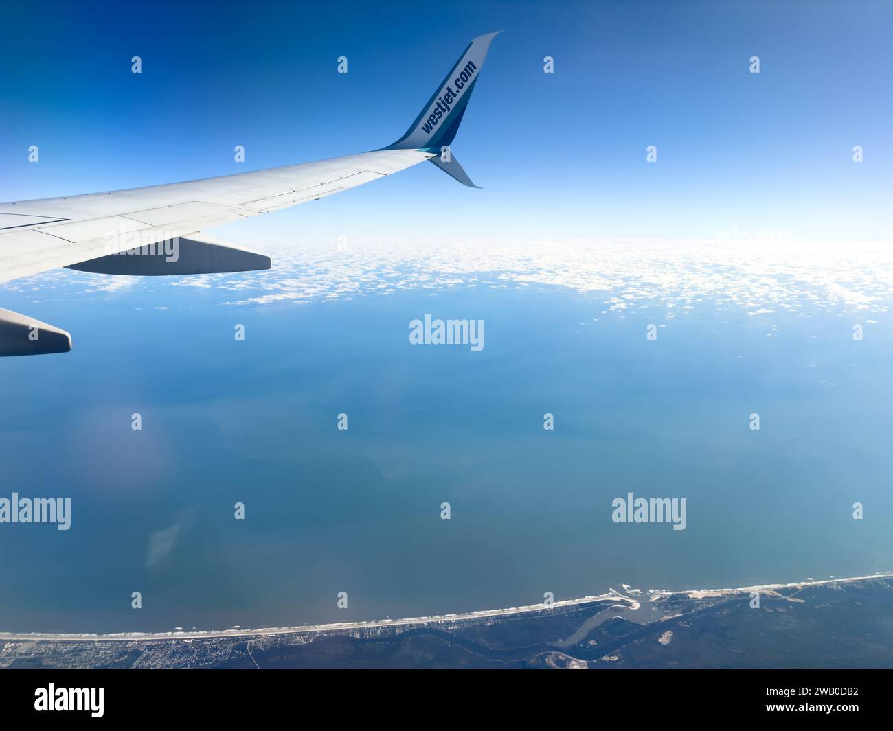 The wing of a Westjet plane as it passes over a Florida beach on a ...