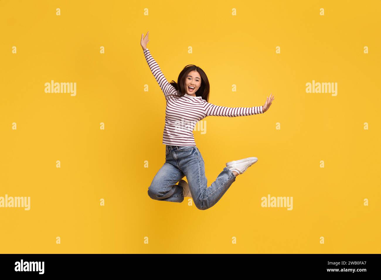 Overjoyed young chinese lady 20s jumping on yellow background Stock ...