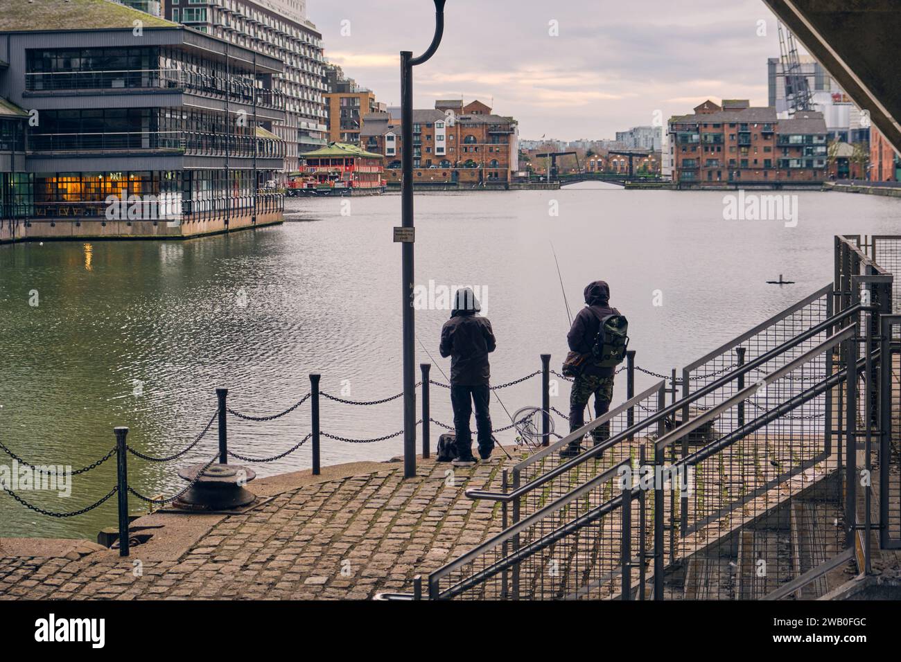 Urban fishing. Two men fishing in Millwall Inner Dock, South Quay ...