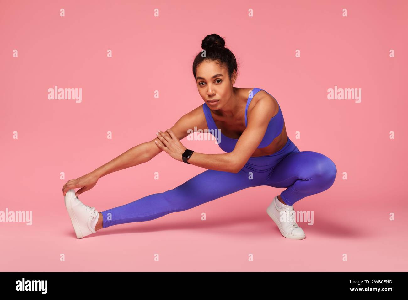 african american sportswoman stretching legs and hamstring muscles ...