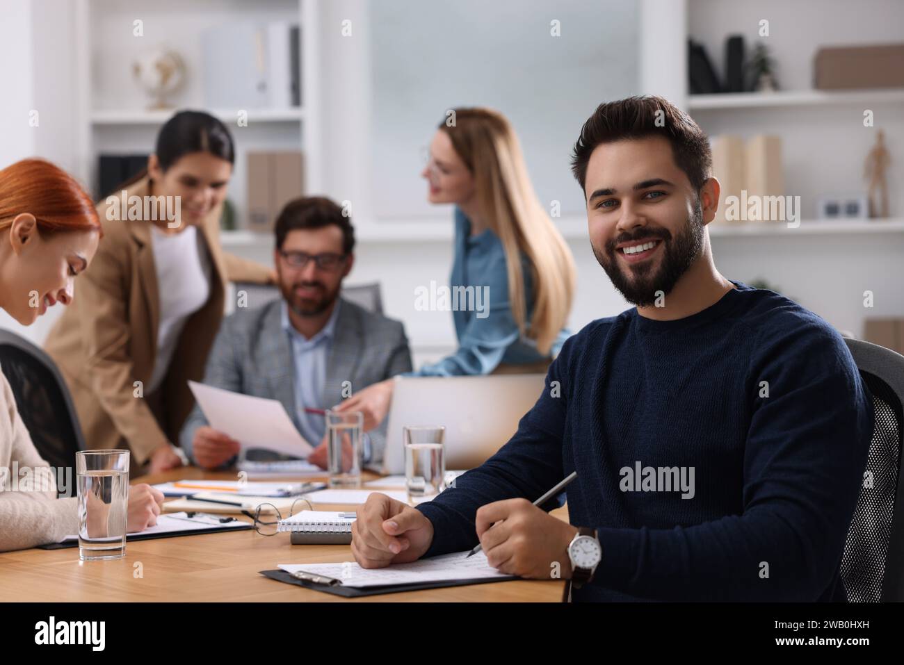 Team of employees working together in office. Happy man with pen and ...