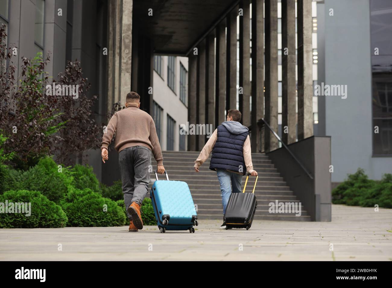 Being late. Men with suitcases running towards building outdoors, back ...