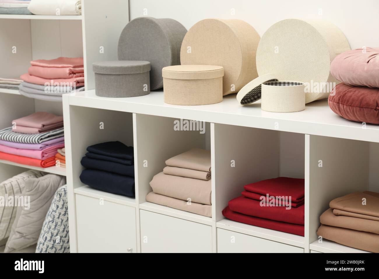 Different colorful bed linens and decorative boxes on display in home ...