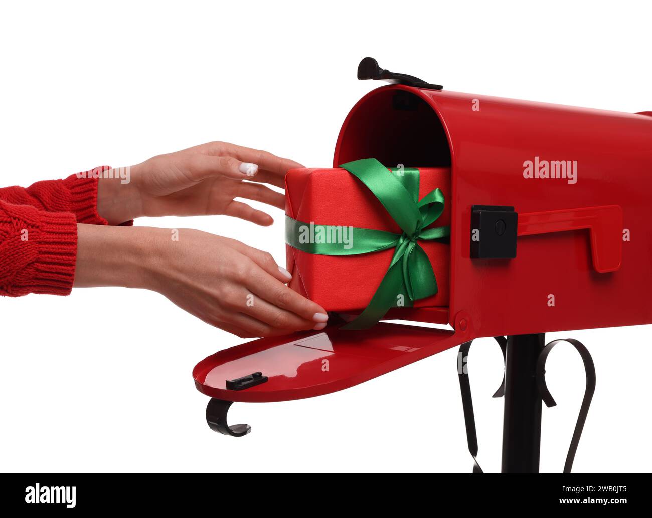 Woman putting Christmas gift into mailbox on white background, closeup ...