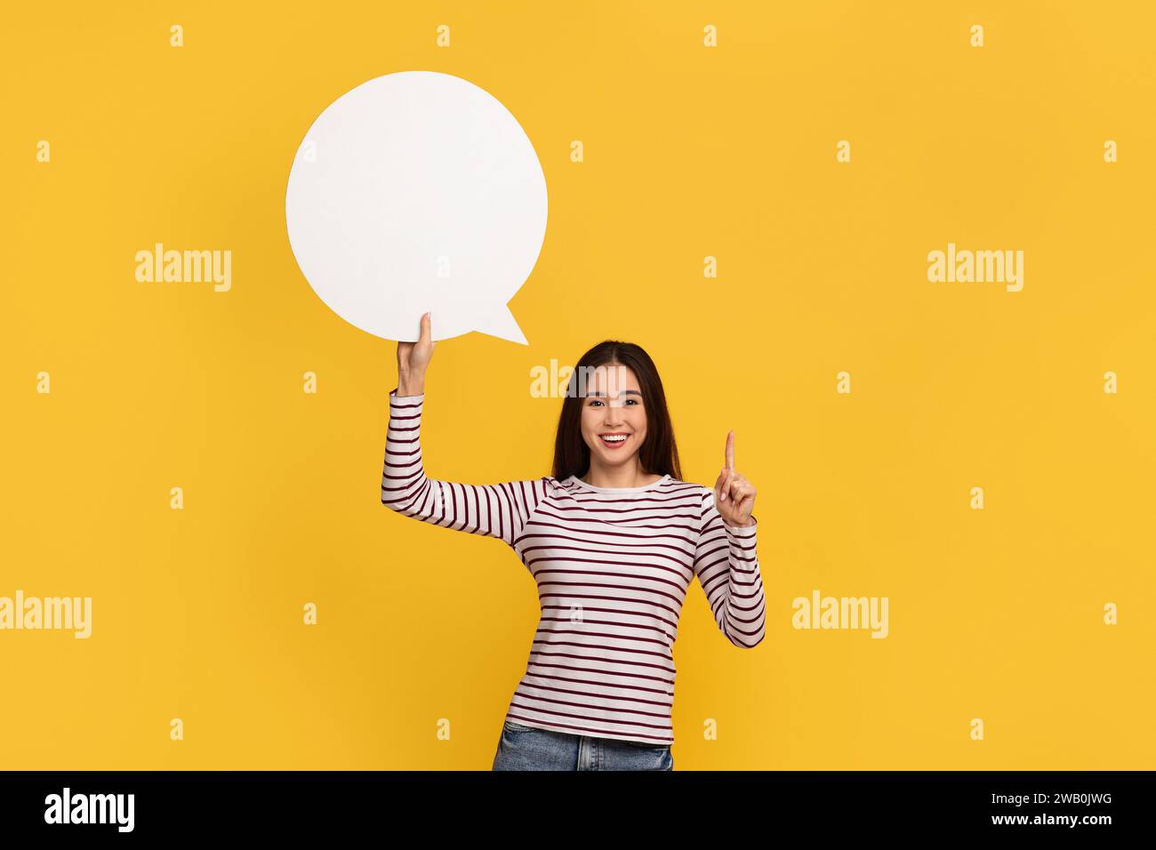 Asian lady smiles gladfully points up, shows white communication bubble ...