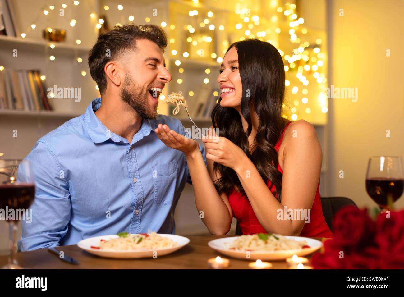 Couple sharing a playful moment with pasta during romantic dinner Stock ...