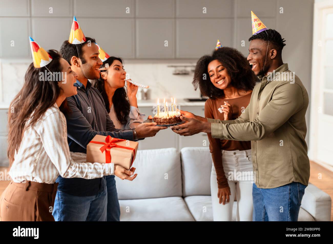 Diverse group of students celebrating birthday of friend at home Stock ...