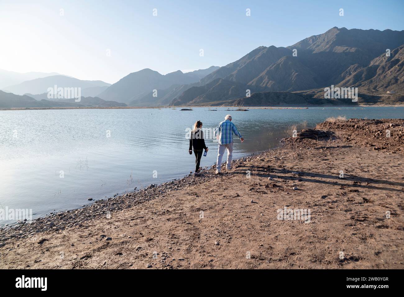 Senior man walking with his granddaughter along the lake shore with ...
