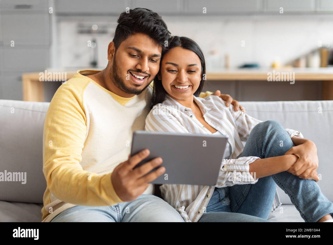 Happy Indian Couple Watching Videos On Digital Tablet While Relaxing At ...