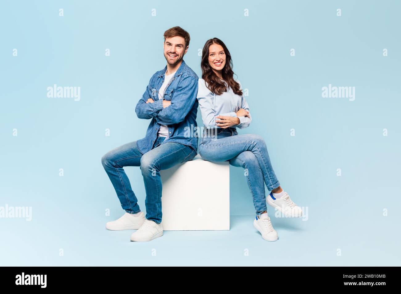 Confident couple in denim, casually seated back to back Stock Photo - Alamy
