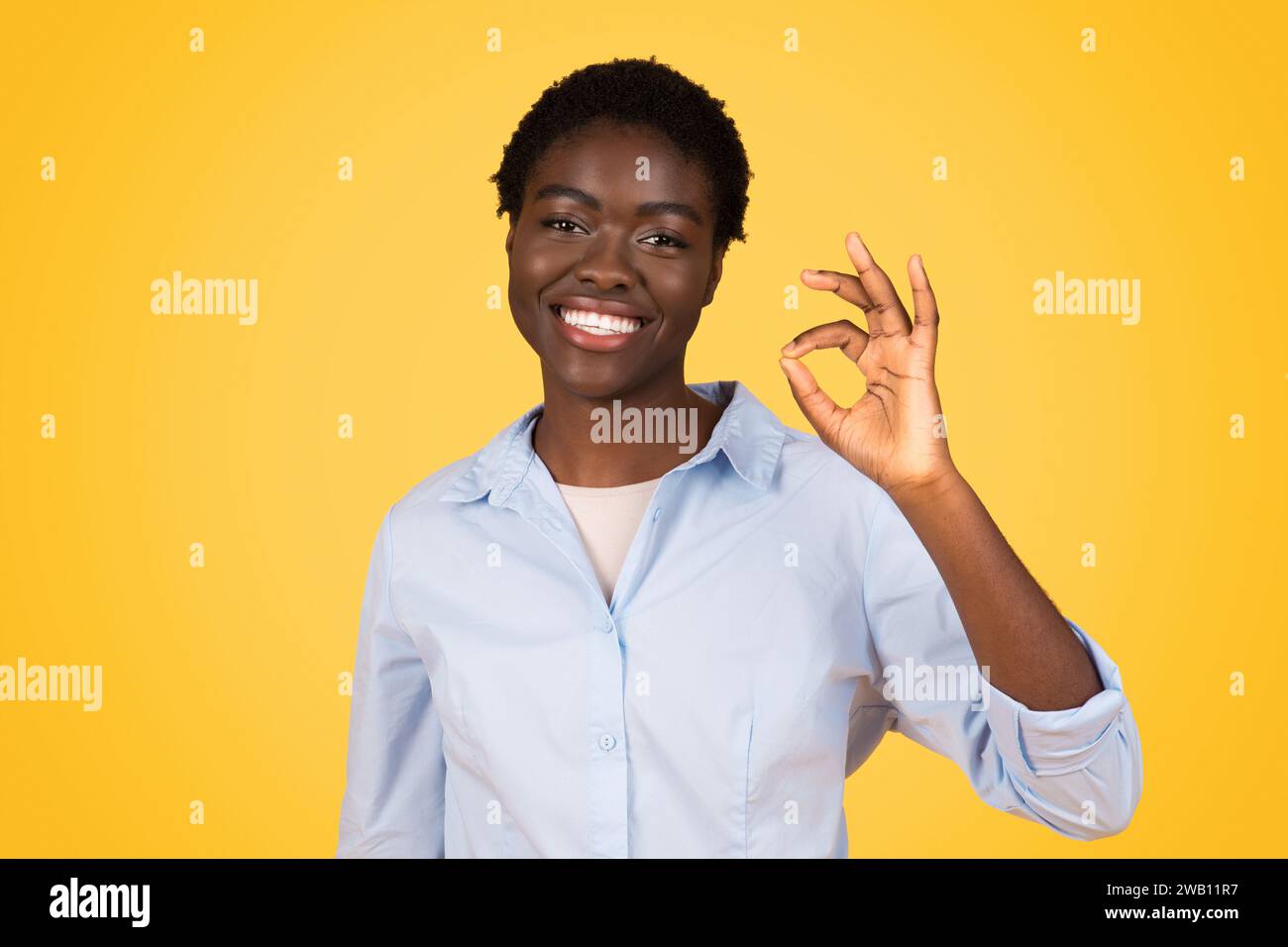 A confident black woman student making an 'OK' gesture, her expression ...