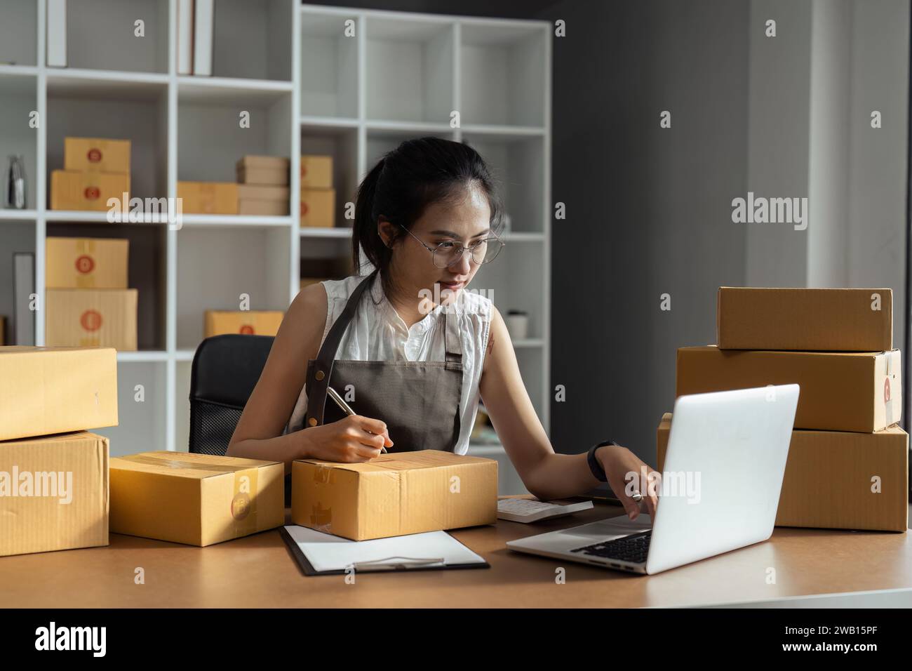 Asian woman write parcel box to prepare for delivery to customer. e ...