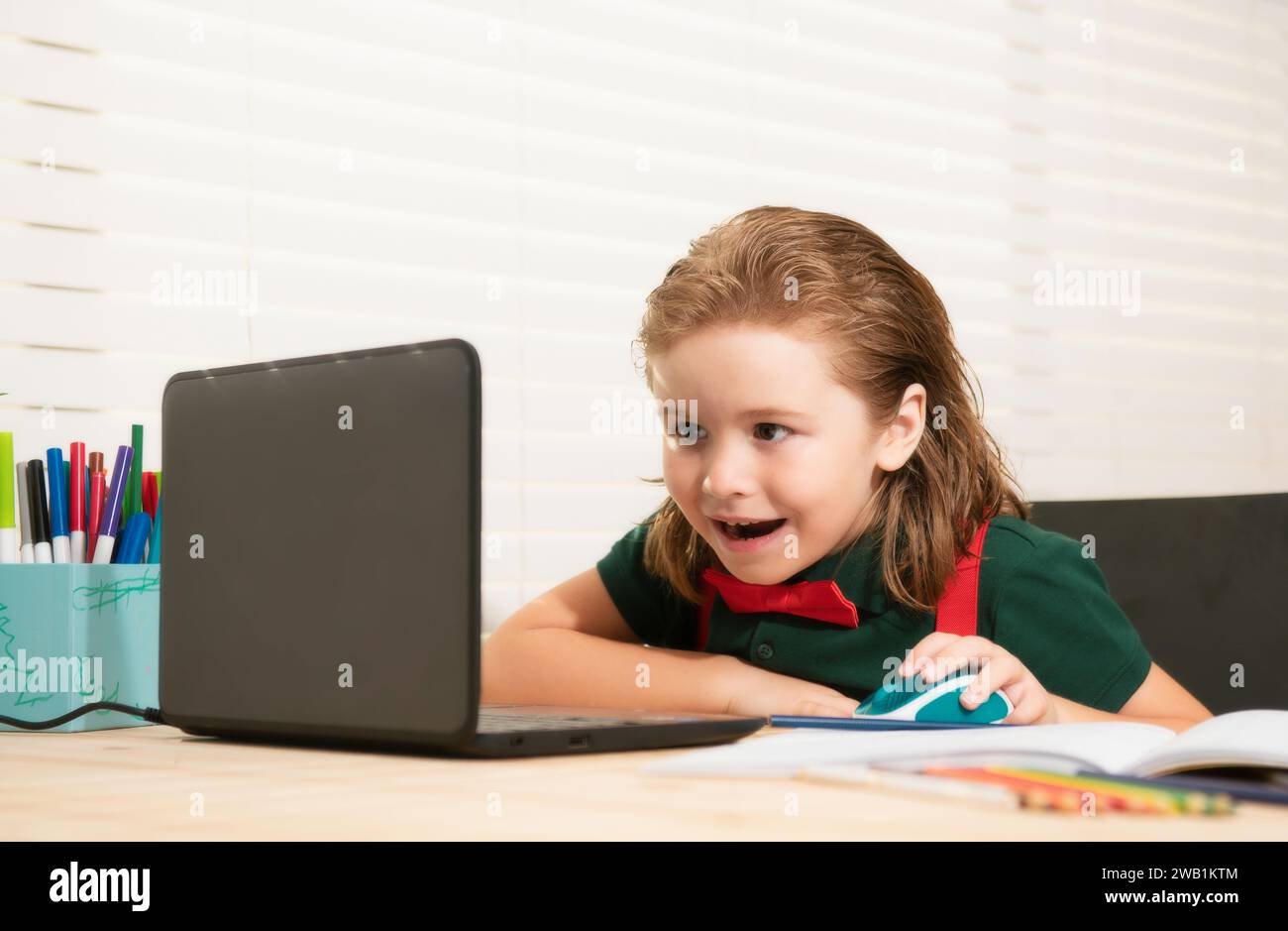 School boy with a happy smiling face studying and using computer laptop ...