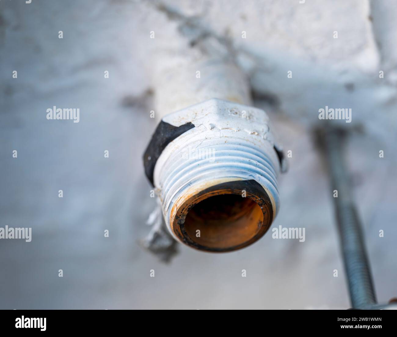 Inside, a black rusty pipe sticks out from the white wall. It is ...