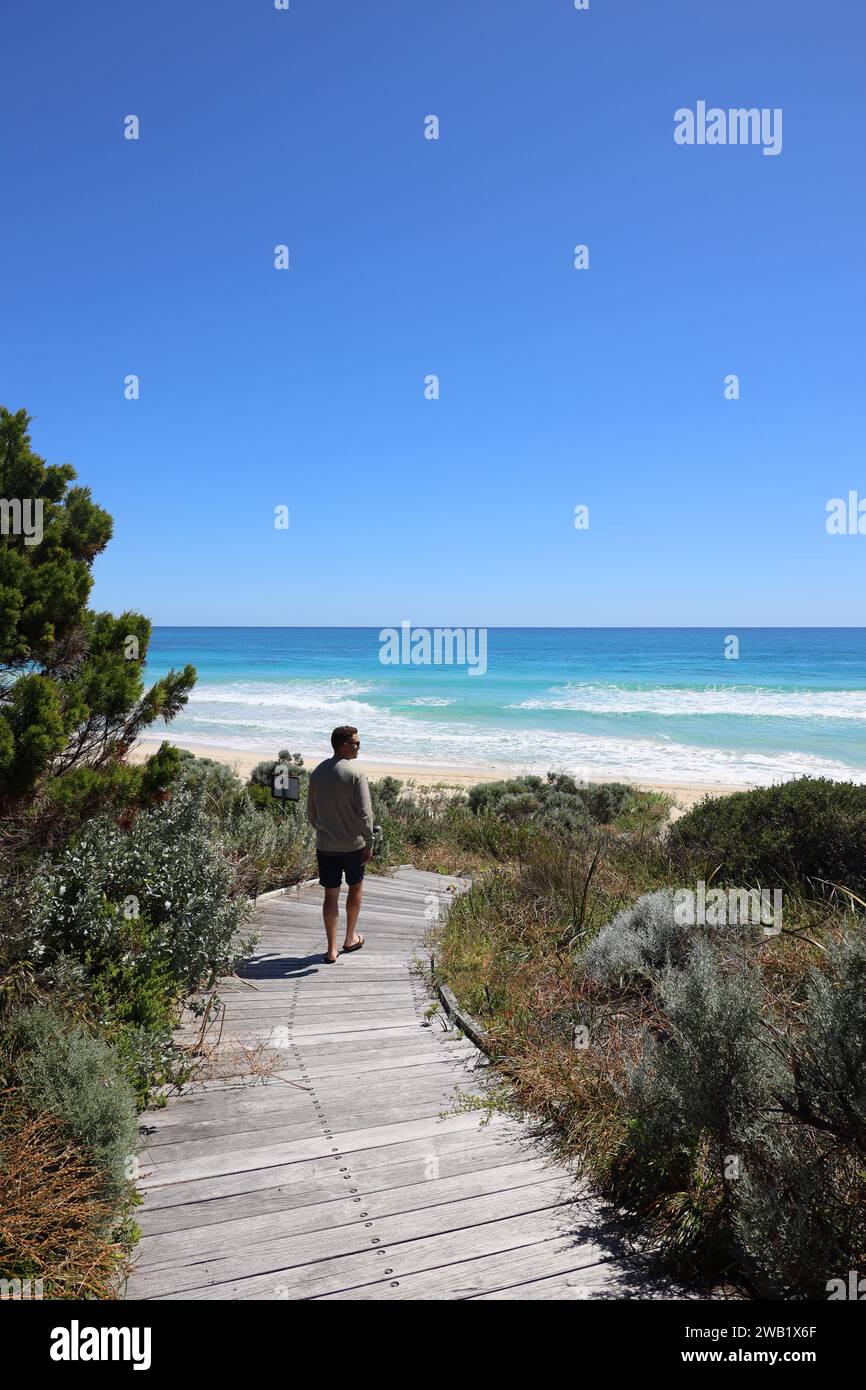 A silhouetted man standing on a path, looking out at the vastness of ...