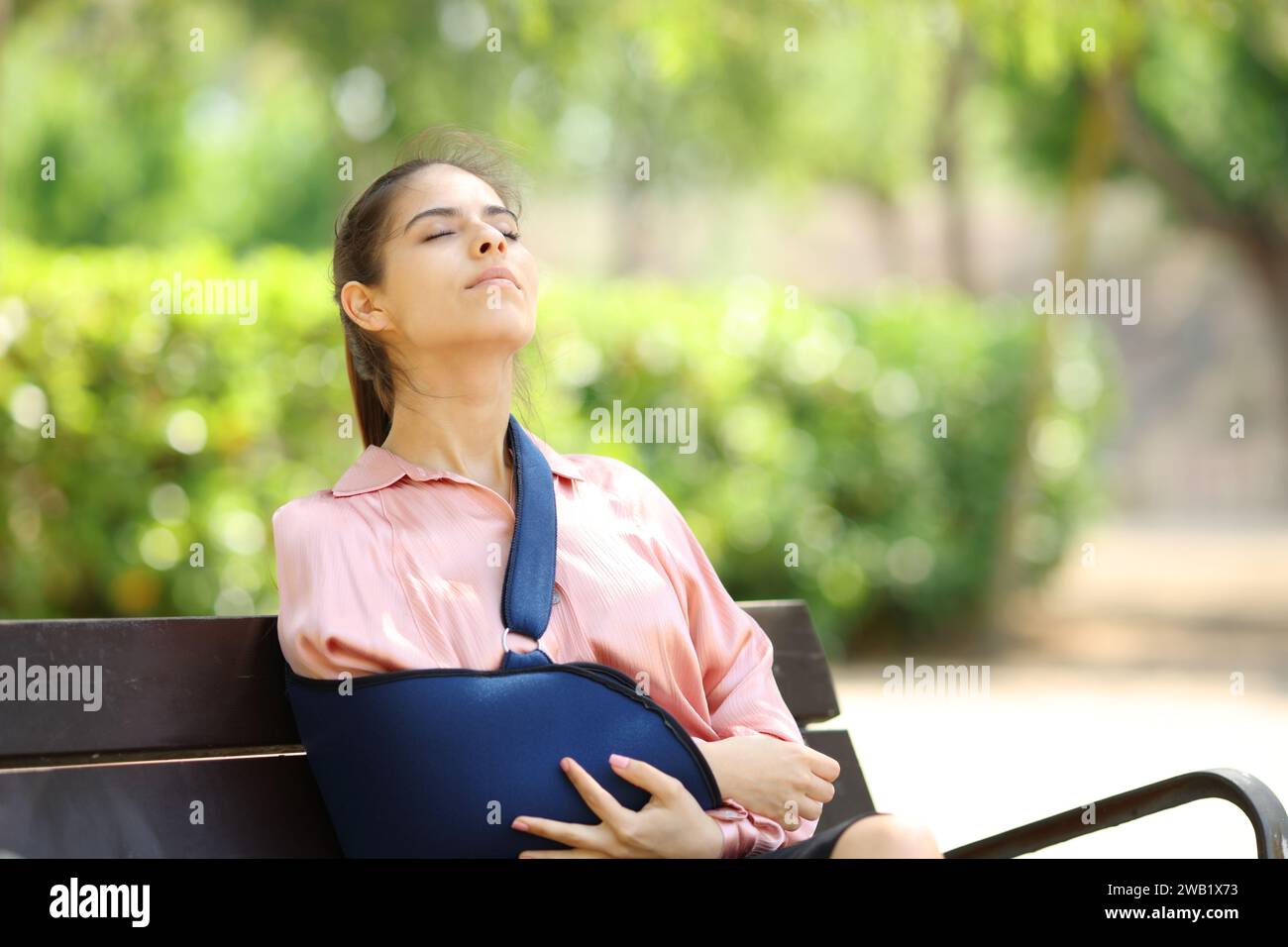 Convalescent woman breathing fresh air sitting in a bench in a park ...
