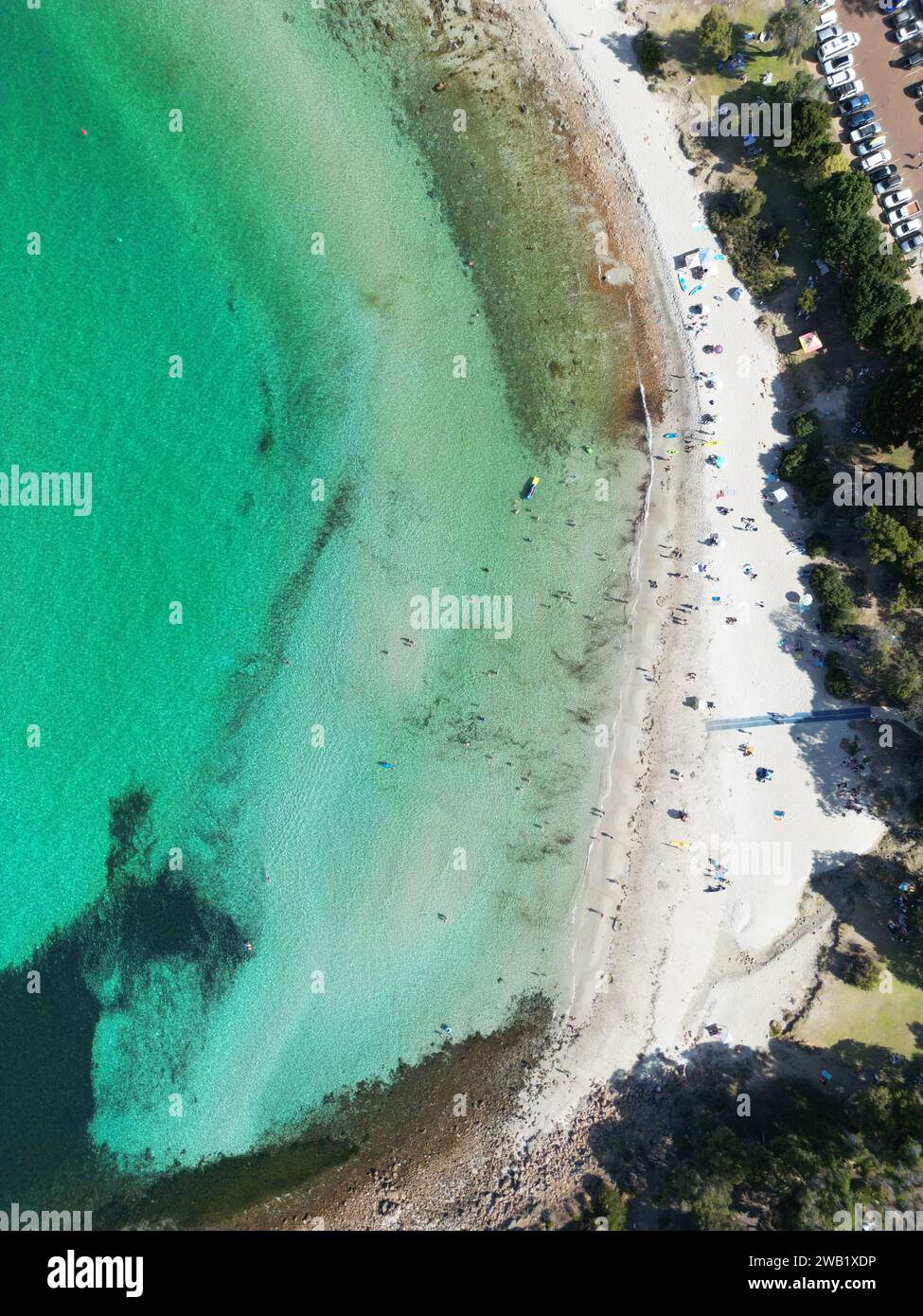 An aerial view of a stunning bay with cars parked along the shoreline ...