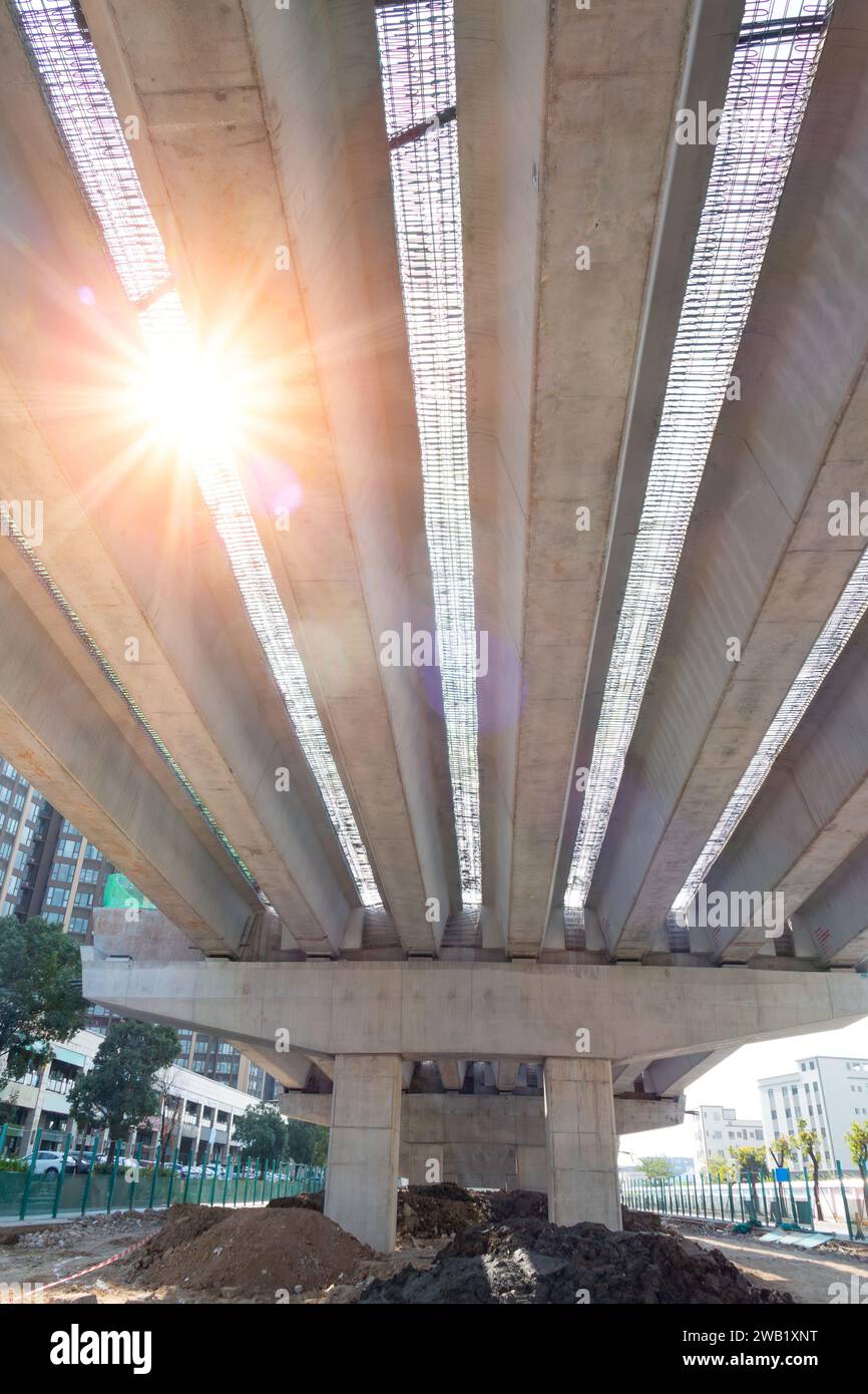 bottom view of a concrete highway under construction against the sun at ...
