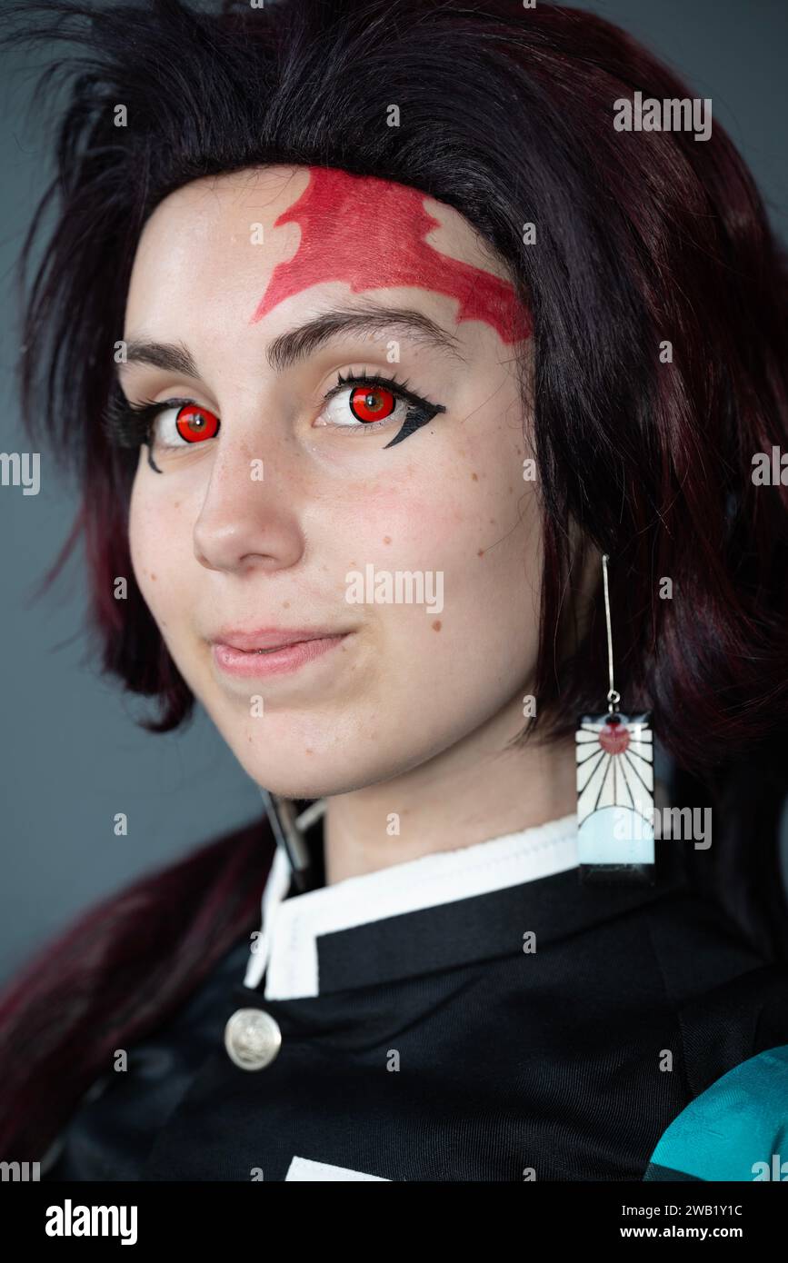 A Caucasian female cosplayer in a blue costume with face paint and red ...