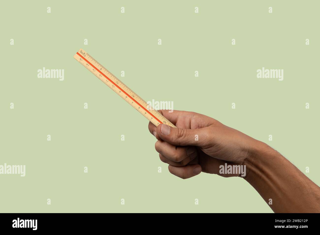 Male hand holding vintage ruler on light green background Stock Photo ...