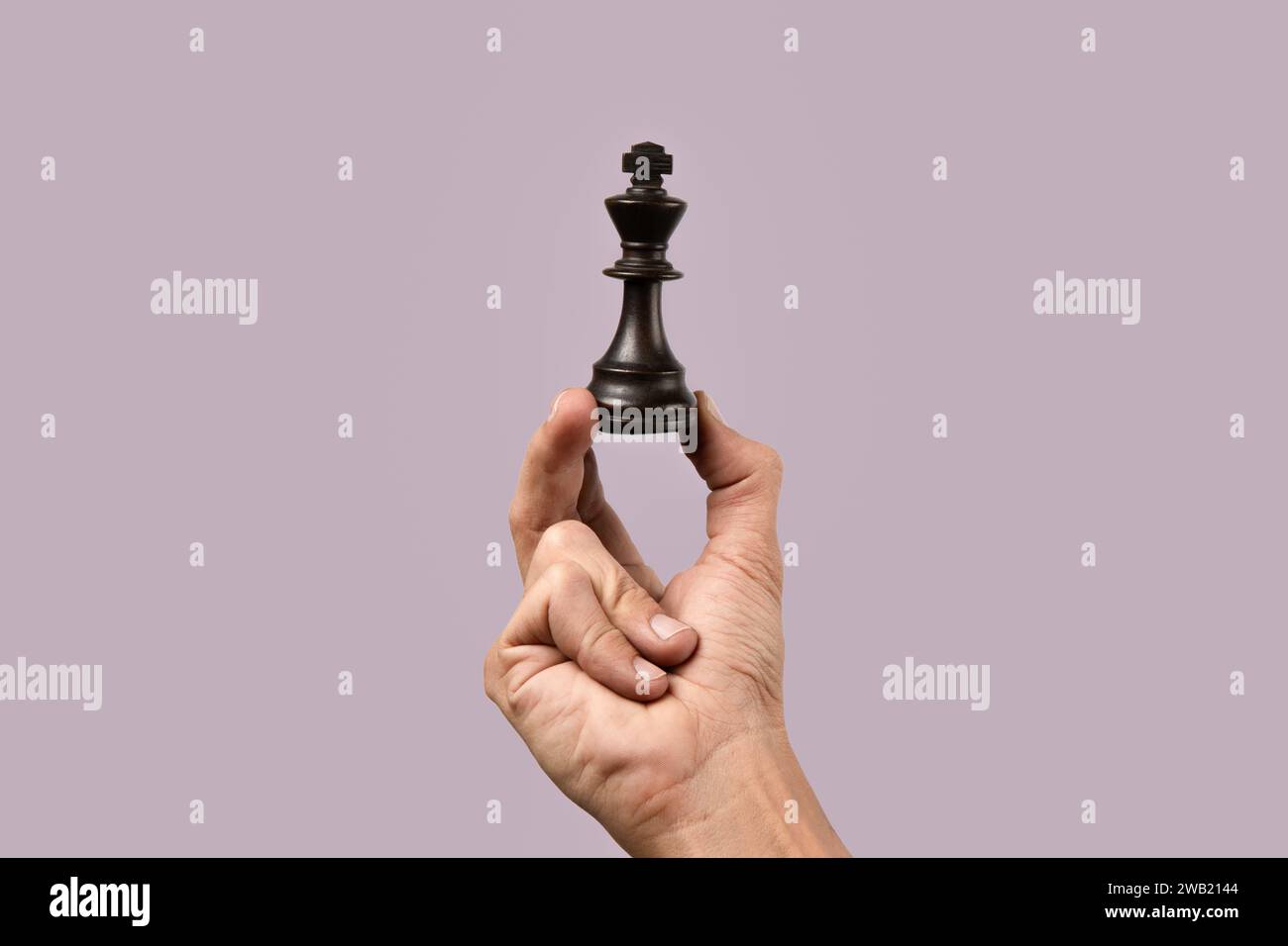 Male hand holding king chess figure on purple background Stock Photo ...
