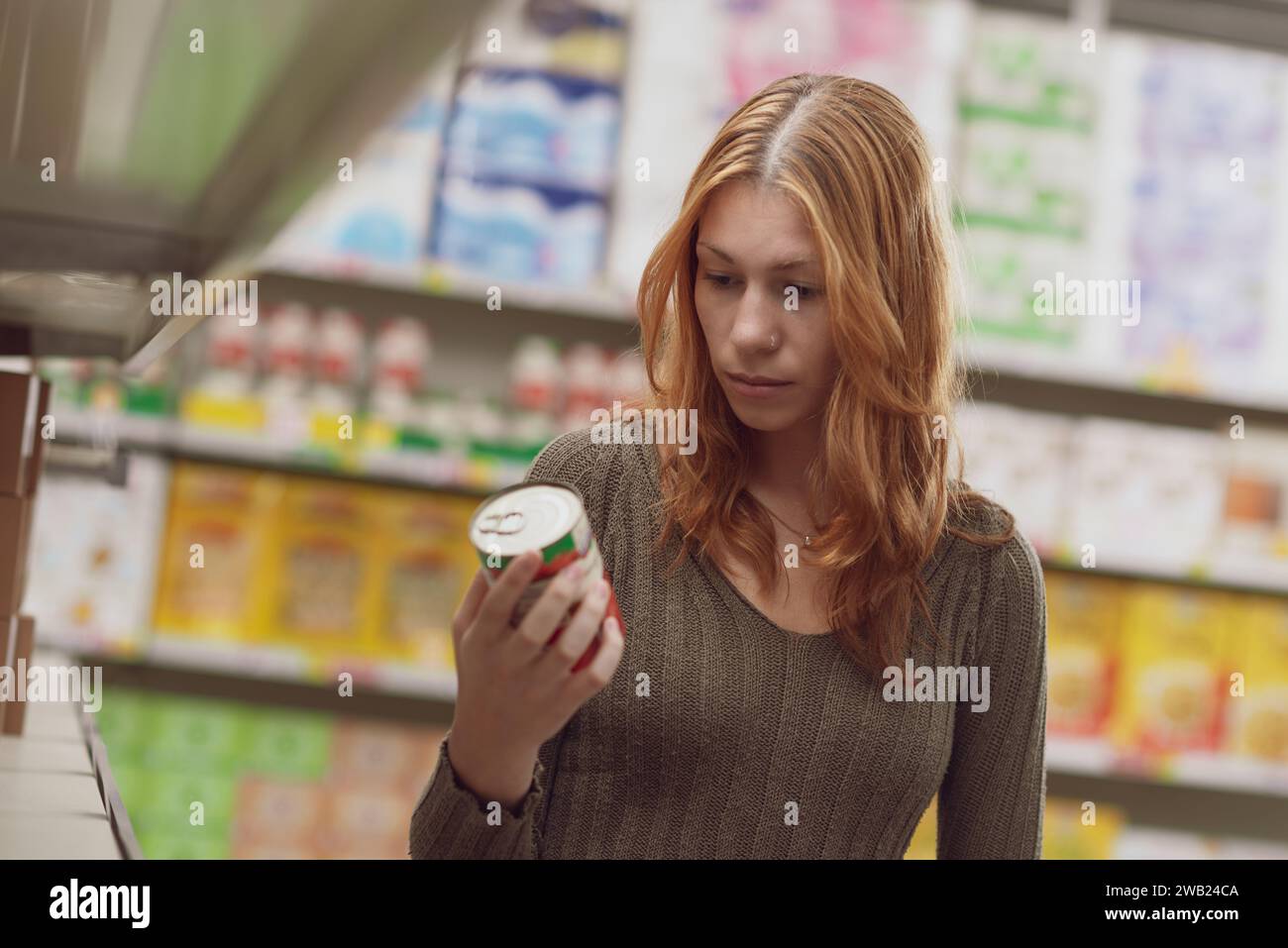 Young woman doing grocery shopping at the supermarket, she is holding a ...