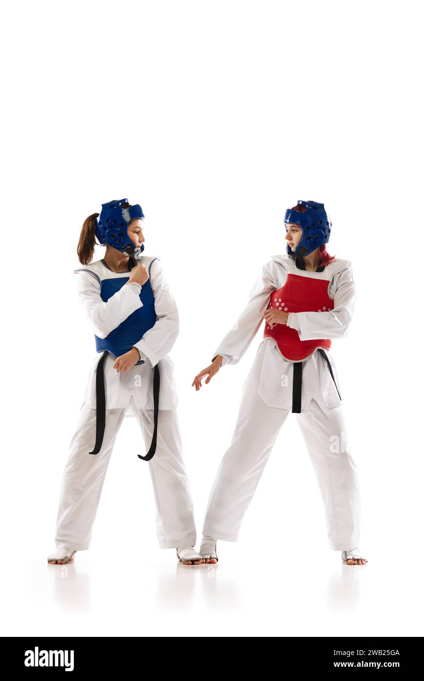 Full-length image of young competitive girls in dobok and helmet ...