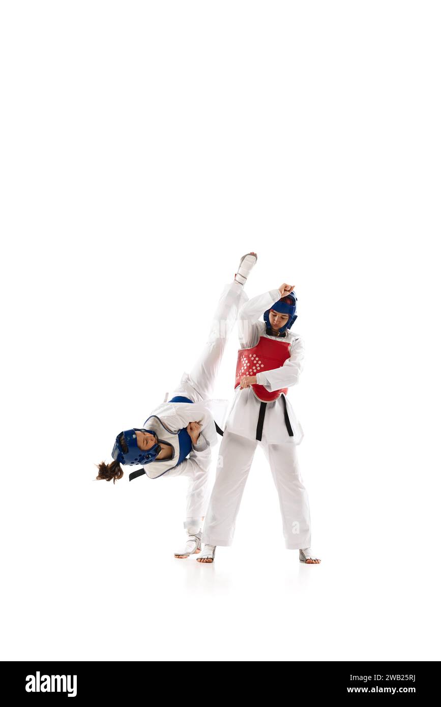 Two young girls in dobok and helmet training, practicing taekwondo ...