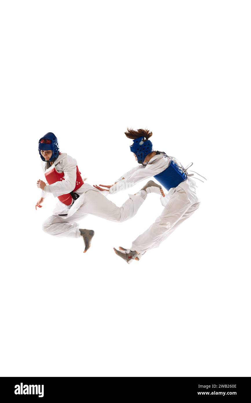 Two young girls in dobok and helmet training, practicing taekwondo ...