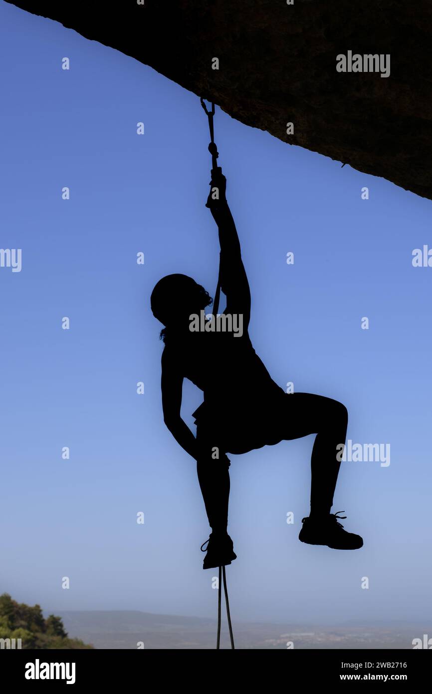 Image of a determined and brave girl climbing an imposing rock face ...