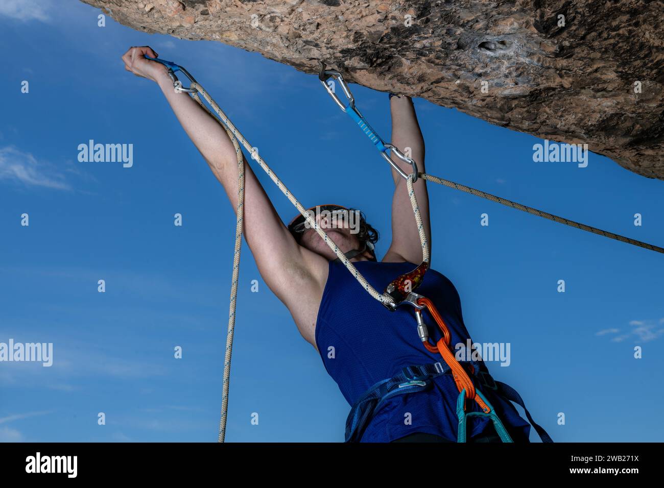 Image of a determined and brave girl climbing an imposing rock face ...