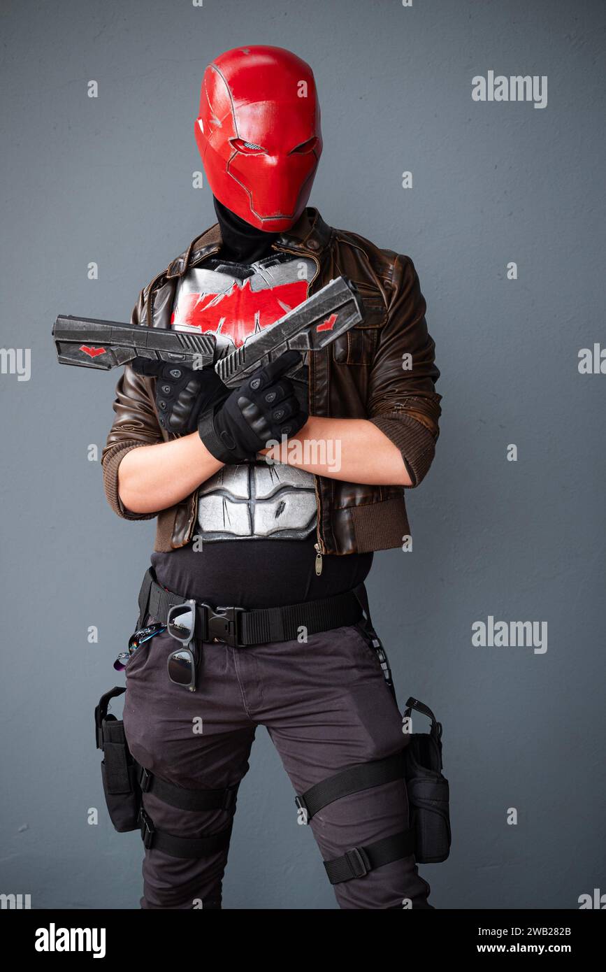 A male cosplayer in a costume with a red helmet, leather jacket, and ...
